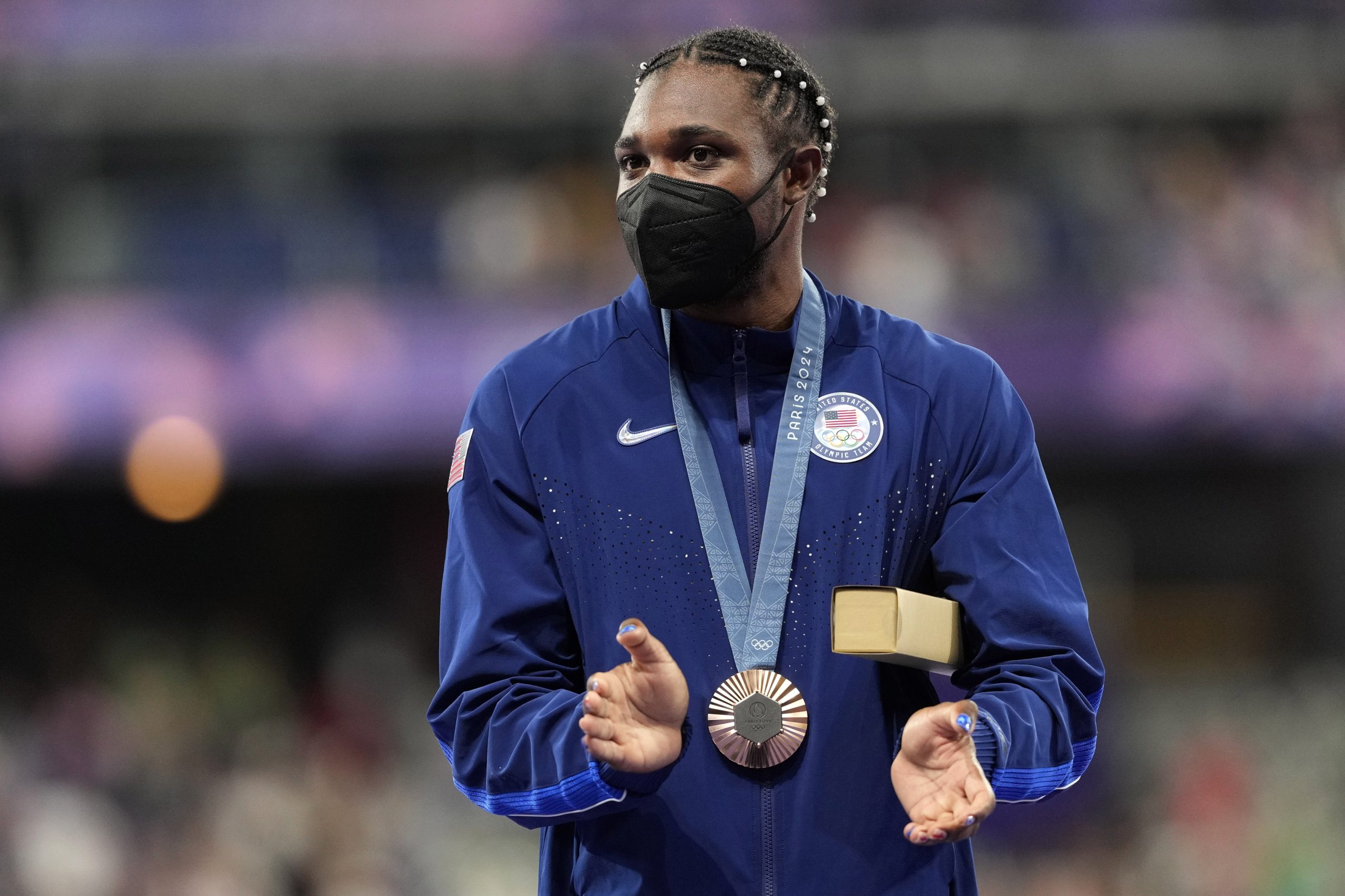 A masked Noah Lyles accepts his bronze medal in the 200-meter final ...
